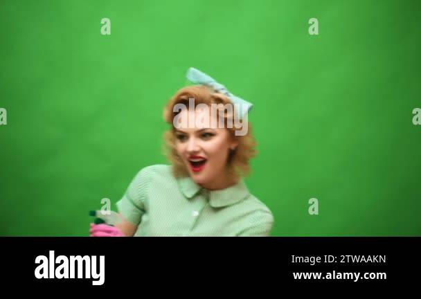 Pin up woman in gloves smiling and wiping dust using a spray and a ...