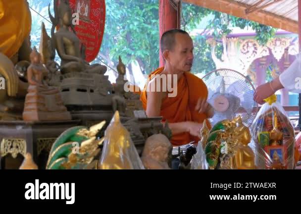 Monk knots a rope or ribbon to the tourists at the Buddhist temple of ...