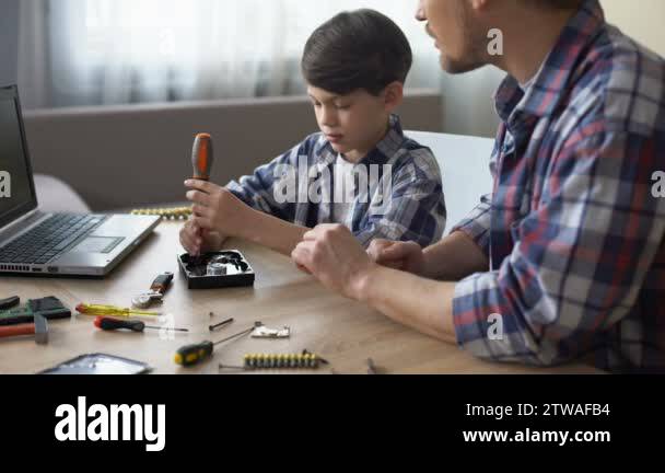 Caring father teaching his little son to repair hard disk drive at home, hobby Stock Video ...