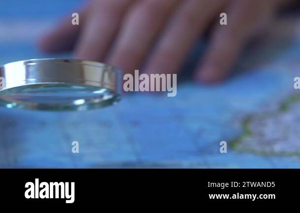 Man looking at map of world through magnifying glass, choosing place to ...