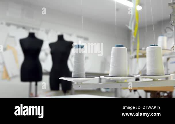 Closeup of three big bobbins with thin white thread on working ...