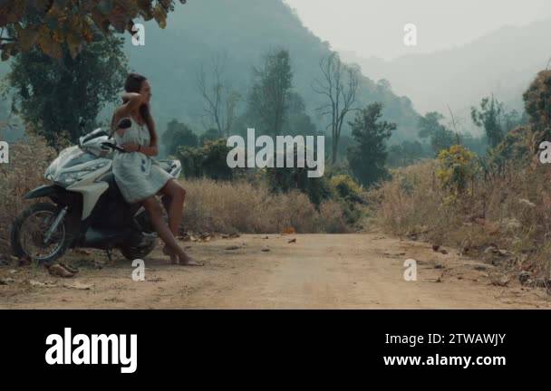 Thailand, Pai. A beautiful, tanned girl in a white dress corrects her ...
