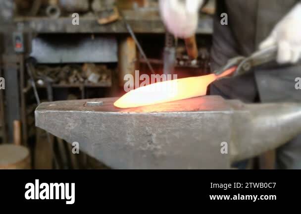 Making the knife out of metal at the forge. Close up blacksmiths hands ...