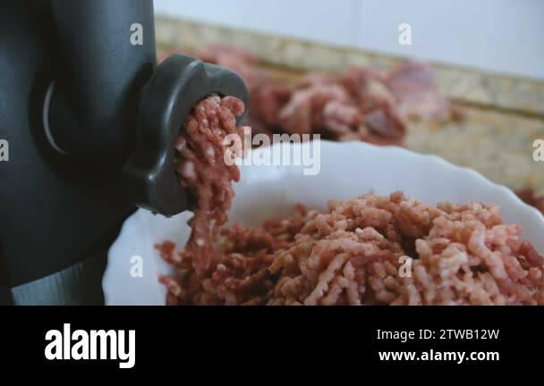 Close-up beef and pork meat and onion through electric meat mincer ...