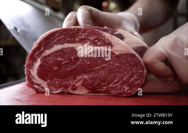 Butcher in gloves cuts carcass of red meat. Action. Close-up of ...