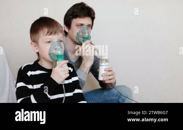 Use nebulizer and inhaler for the treatment. Man and boy inhaling ...