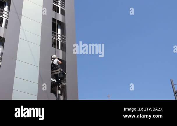 Industrial climber is washing, cleaning window of a modern office ...