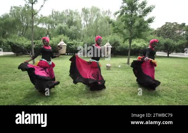 Three african women dancing a folk dance in traditional costumes with ...