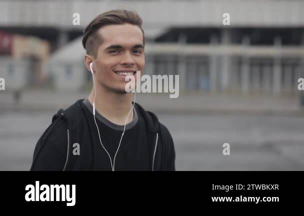 Portrait of attractive male runner with headphones running at stadium ...