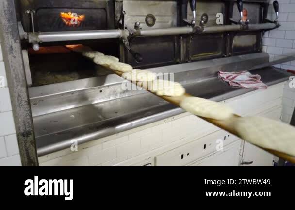 Traditional Italian bakery. The woman Baker puts the bread in the oven ...