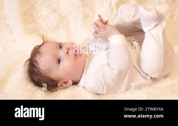 Baby in body lies on his back, playing with his hands, legs and talking ...