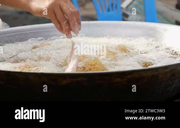 Street food in Thailand and Asia. Large boiling vat in which woman hand ...