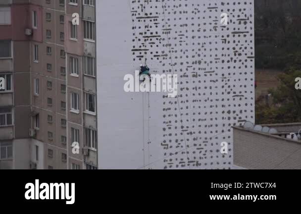 High-altitude work. The man works on high-rise works cladding ...