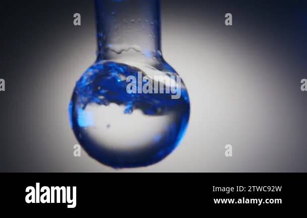 Lucid water with shining tints is shaken in a round flask in a chemical ...