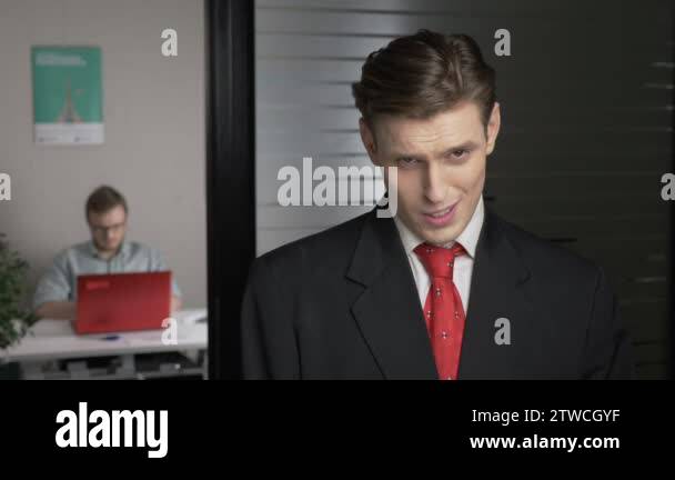 Young successful man in a suit shows Yes by shaking head. Man works on ...