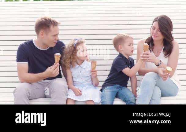 Family mom, dad, son and daughter are sitting on the bench in summer ...