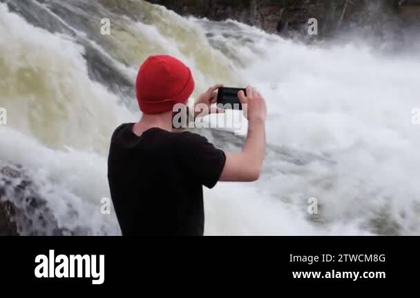 Portrait of a Tourist who stands under a waterfall, takes pictures, how ...