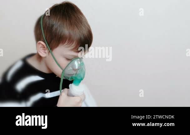 Use nebulizer and inhaler for the treatment. Boy inhaling through ...