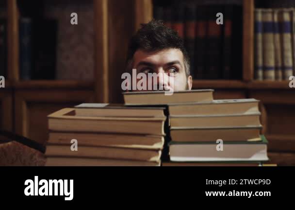 A funny bearded man. Man with happy face between piles of books in ...