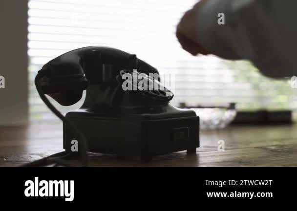 Man picking up the receiver and dialing a number on a vintage rotary ...