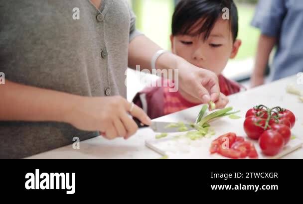 Curious little boy is watchnig his mother prepare vegetables for a stir ...