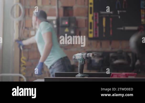 Portrait professional carpenter cutting a piece of wood in his woodwork workshop, using a ...