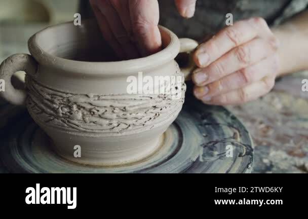 Close-up shot of muddy male potters hands shaping and fixing ears of ...