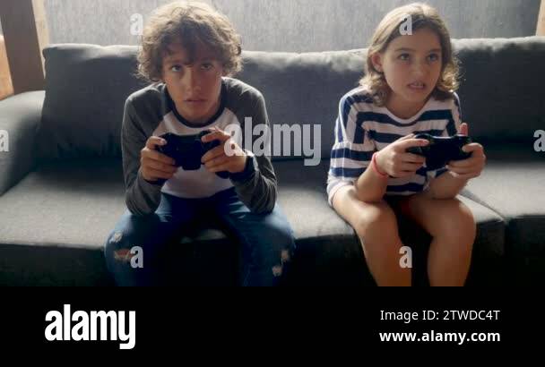Push in of a young pre teenage boy and girl playing video games ...