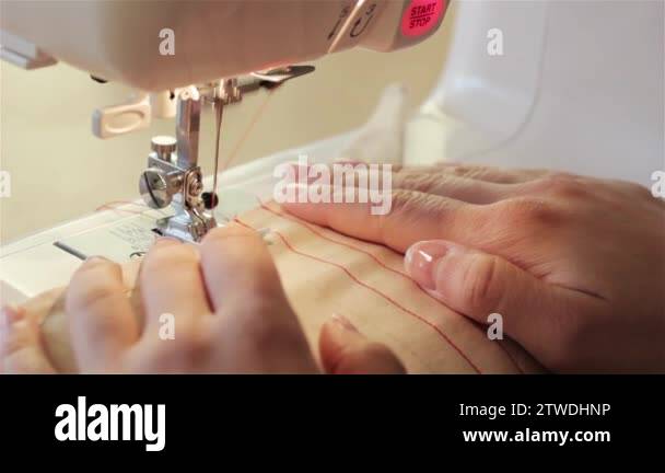 A woman working on a sewing project as she cuts fabric and sews it on a ...