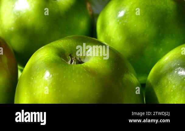 Beautiful green apples stand on a plate. A green fruit turns in front ...