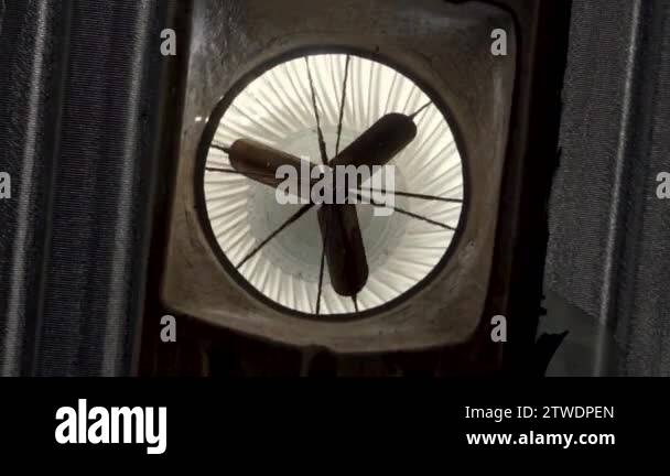 Old rusty industrial ventilation fan turning slowly in a side wall of a ...