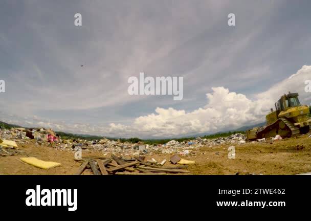 Caterpillar bulldozer pushing a pile of trash in a landfill junkyard ...