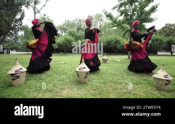 Three african women dancing a folk dance in traditional costumes with ...
