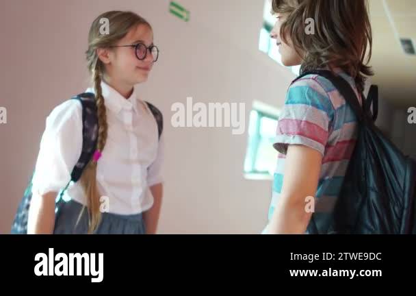 Schoolchildren, a girl and a boy are talking in the school hallway ...