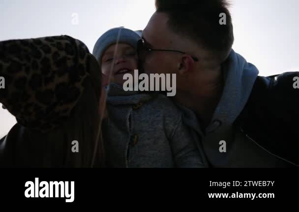 Parental kiss for child in sunlight, good mood young married couple ...