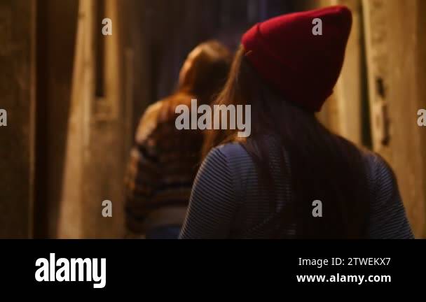 Two young scared women walking on the narrow mysterious dangerous ...