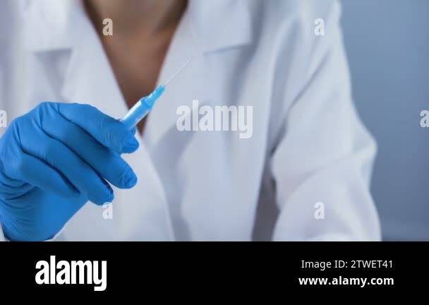 Female nurse preparing injection syringe, filling with ampoule liquid ...