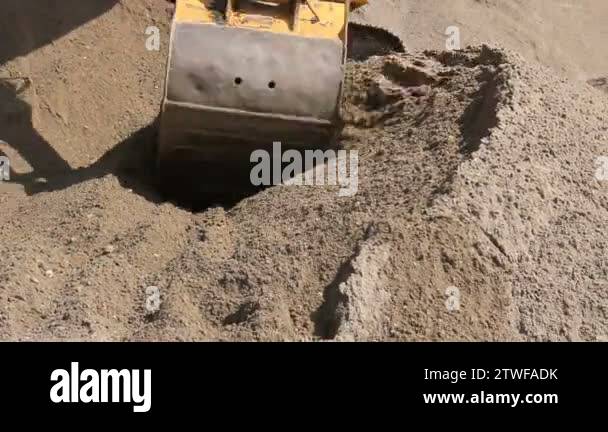 Excavator is preparing pile of sand for loading in truck on building ...