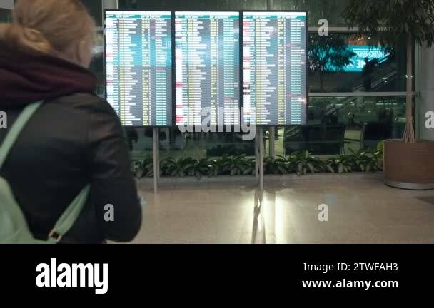Girl wait for departure in the airport, departure and arrivals board ...