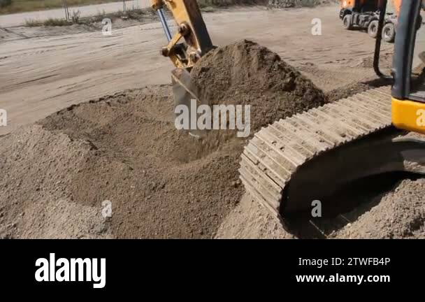 Excavator is preparing pile of sand for loading in truck on building ...