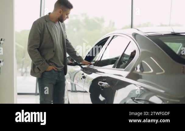 Stylish guy is choosing new automobile walking around luxury car and ...