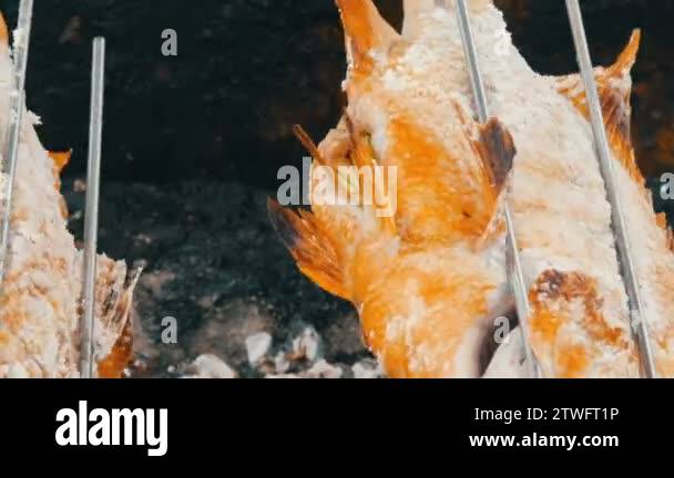 National Thai dish, fried fish on spit in salt and with greens close up ...