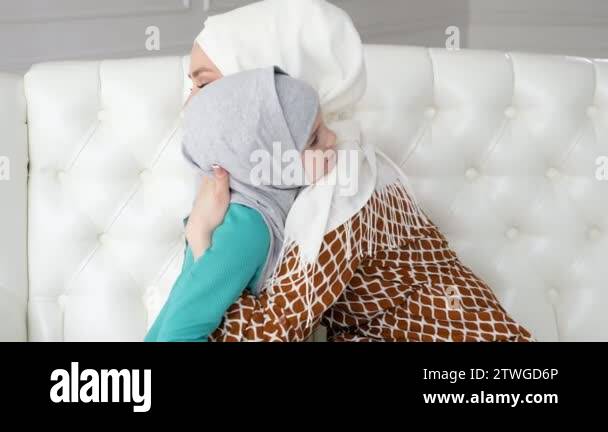 Muslim mom and her little daughter in hijabs are hugging sitting on the ...