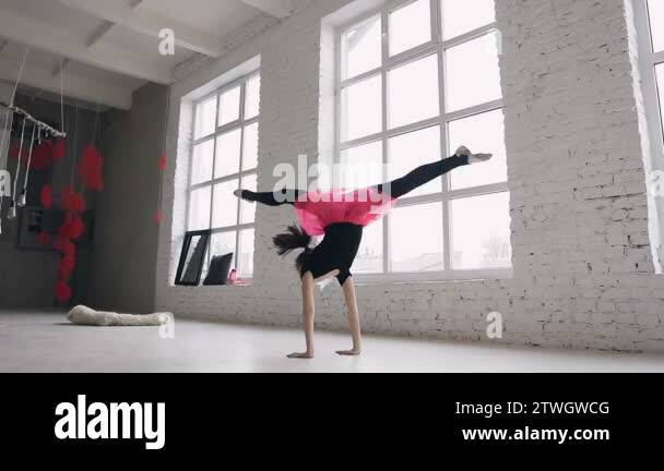 Gymnastics school. Cute gymnast girl performs a back flips with hands ...