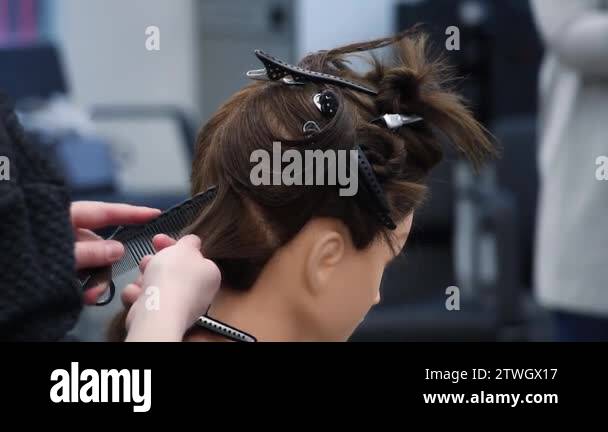 beginner hairdresser practices new skills on a dummy head, combs and ...