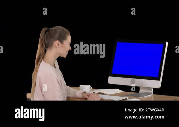 Girl sitting in front of the computer monitor and watching something ...