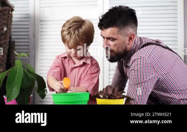 Planting and care of plants. Cute child boy helping his father to care ...