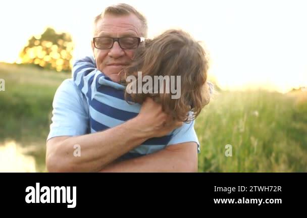 Close-up of a grandfather hugging his grandson. The curly-haired boy ...