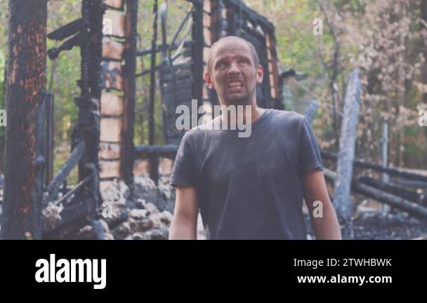 Portrait of a sad man on the background of a burned house, after fire ...