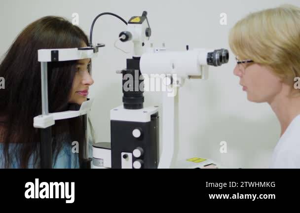female doctor optometrist, ophthalmologist with non contact tonometer is cheking patients vision ...